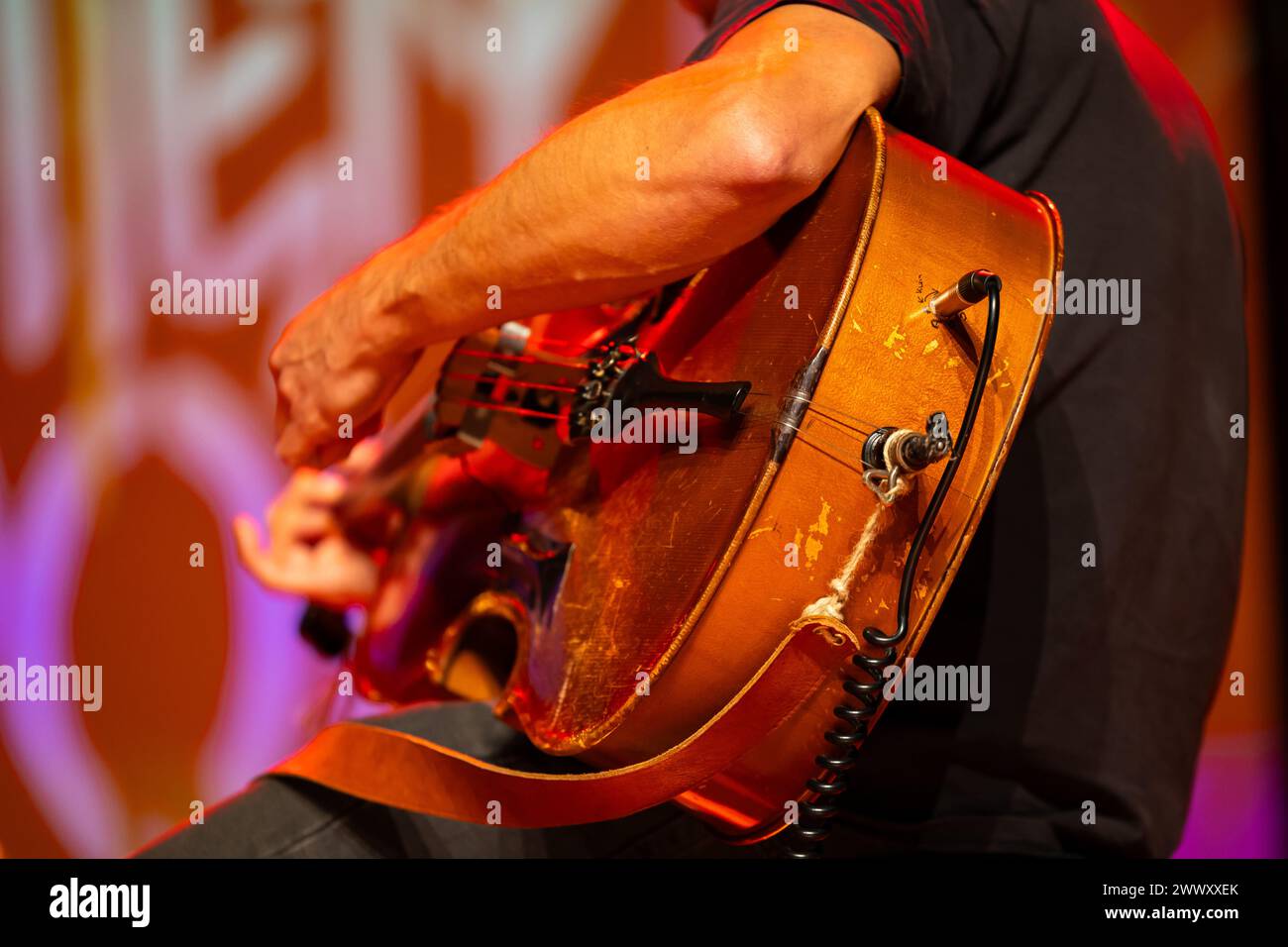 Cellist playing cello on the stage in non conventional way. Photo taken ...