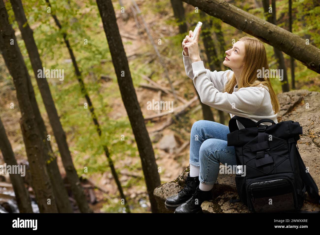 Side view of blonde young woman traveler taking photo of scenery in the ...
