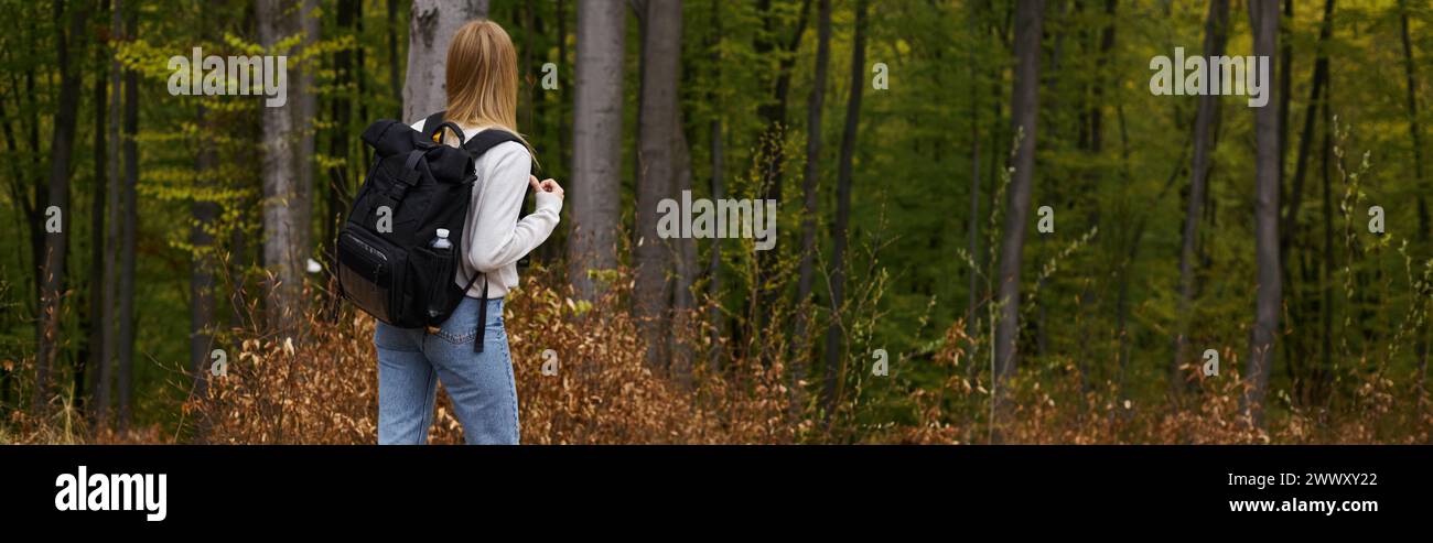 Back view of blonde woman adventurer walking through the forest ...