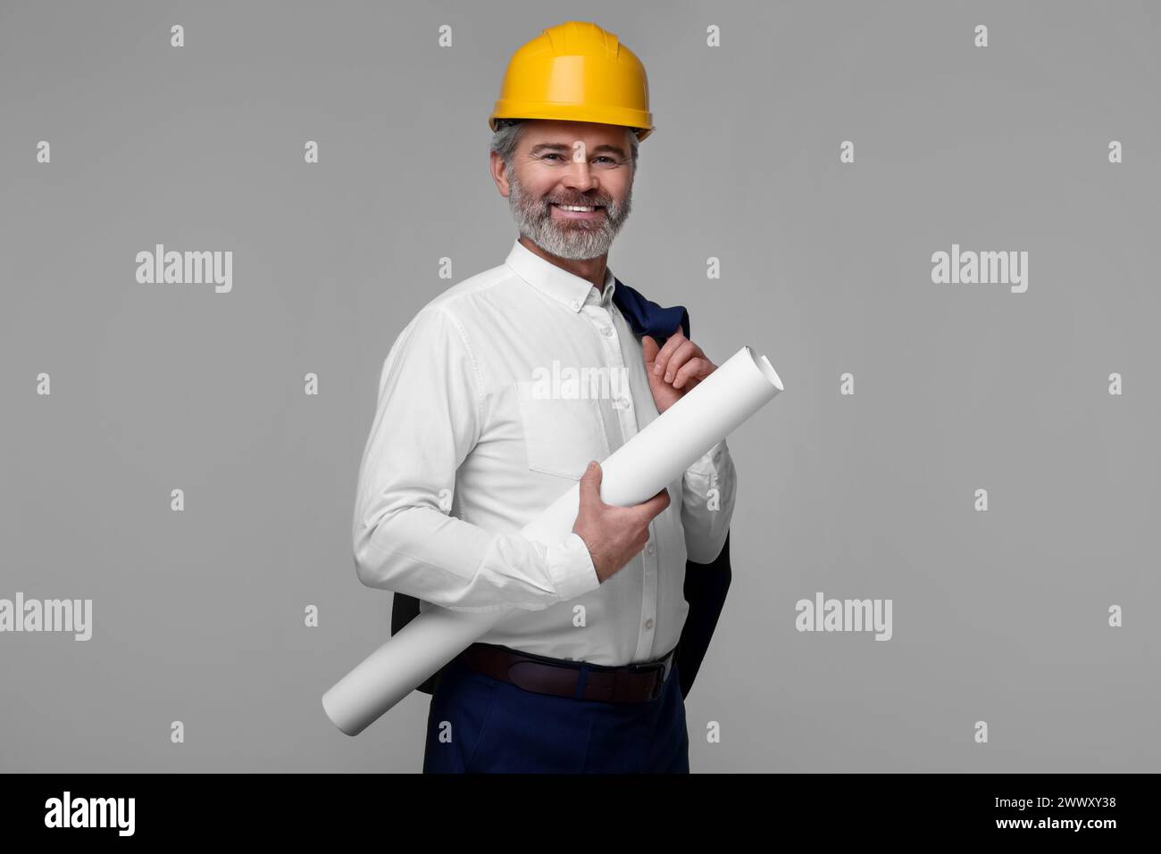 Architect in hard hat holding draft on grey background Stock Photo - Alamy