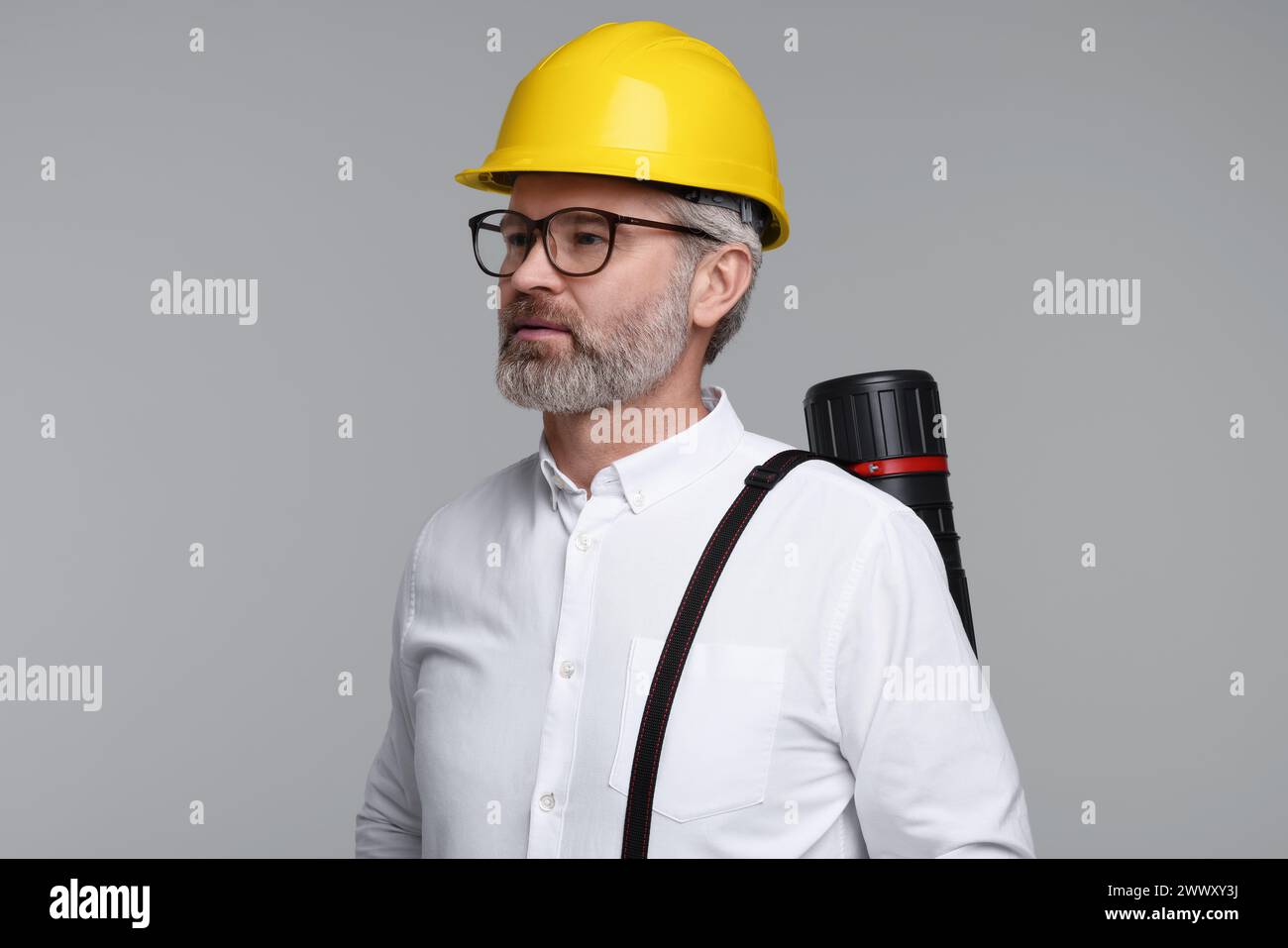Architect in hard hat with drawing tube on grey background Stock Photo ...
