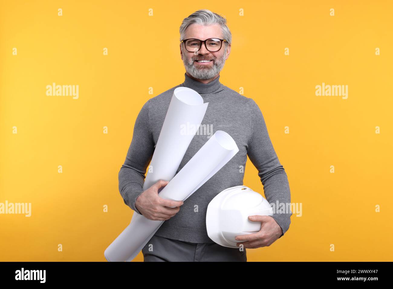 Architect with hard hat and drafts on orange background Stock Photo - Alamy