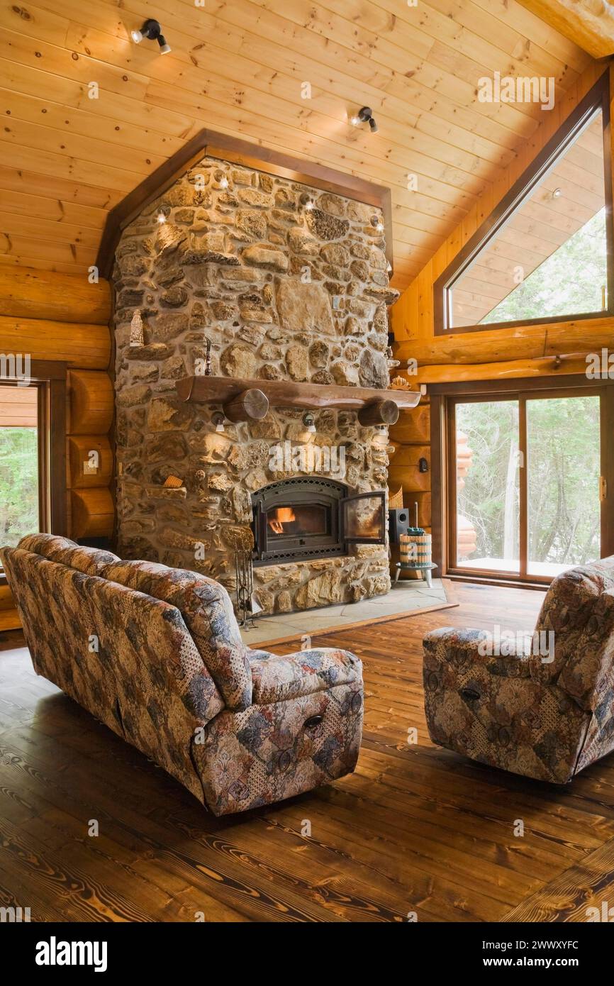 Upholstered sofas with lit fieldstone and porous rock fireplace in ...