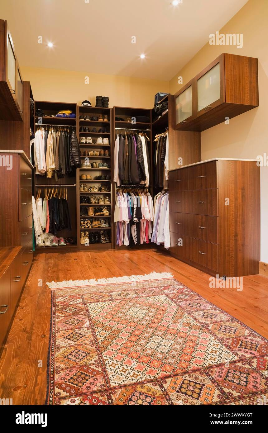 Walk-in closet with assorted men's and women's clothes and carpet in ...