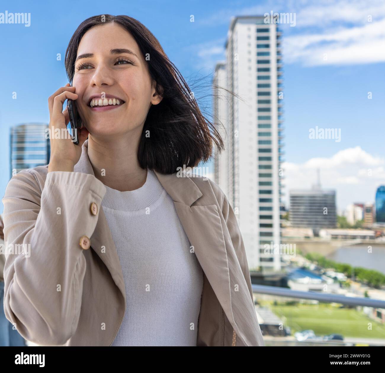 A beautiful young woman is happily chatting on her mobile phone Stock ...