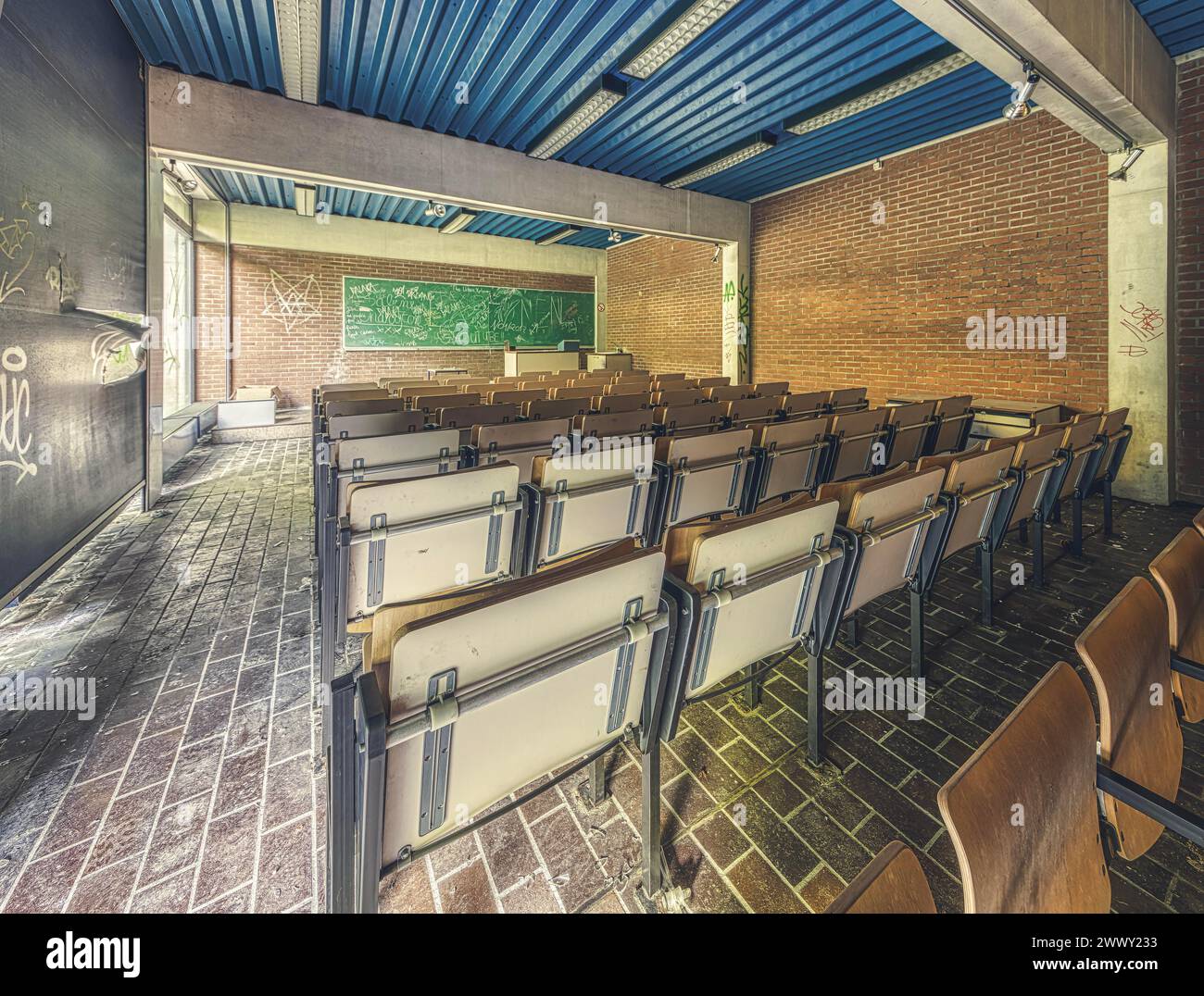 Abandoned classroom with dirty floor and neatly aligned seats ...