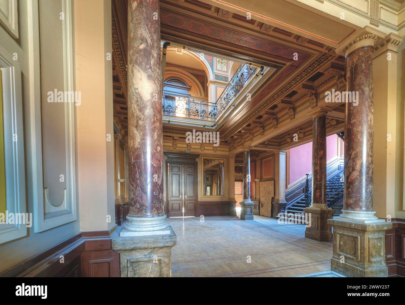 An opulent entrance hall with wood panelling, columns and a colourful ...