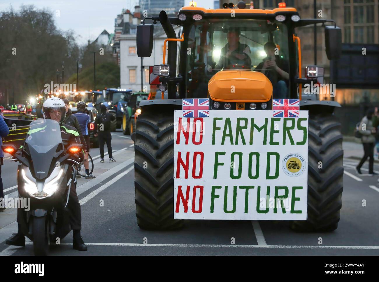 A tractor leads a column of other tractors and displays a placard ...