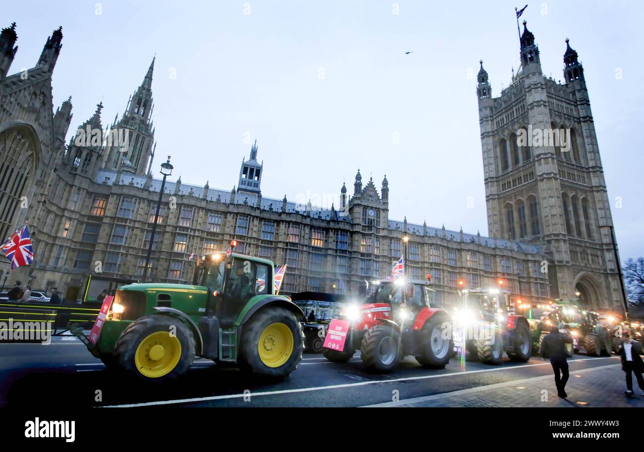 London, UK. 25th Mar, 2024. A line of tractors go slow past the Houses ...