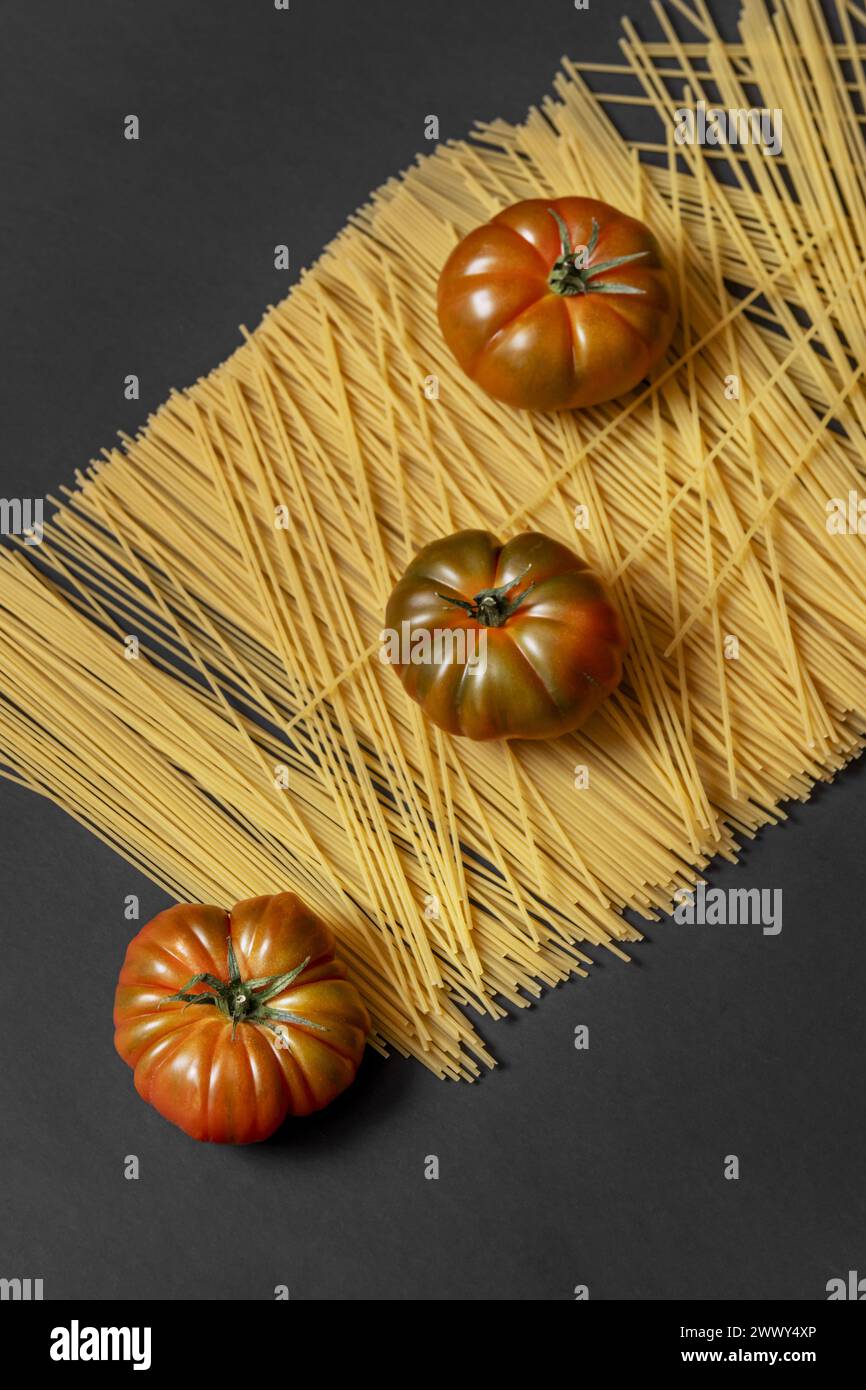a simple still life, raw spaghetti pasta and some ripe tomatoes Stock ...