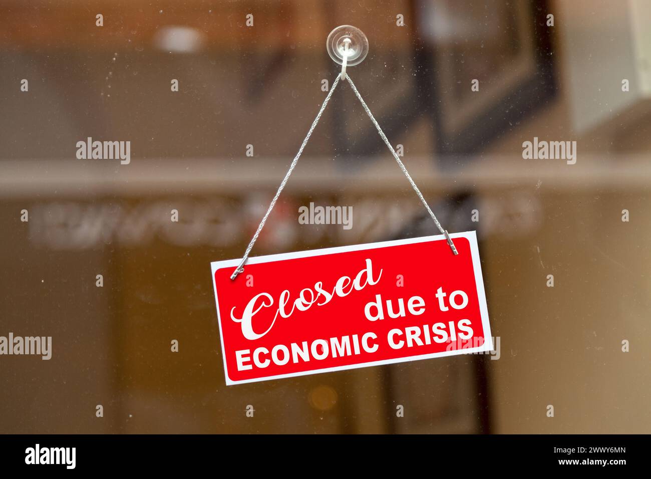 Red sign hanging at the glass door of a shop with written in it "Closed ...