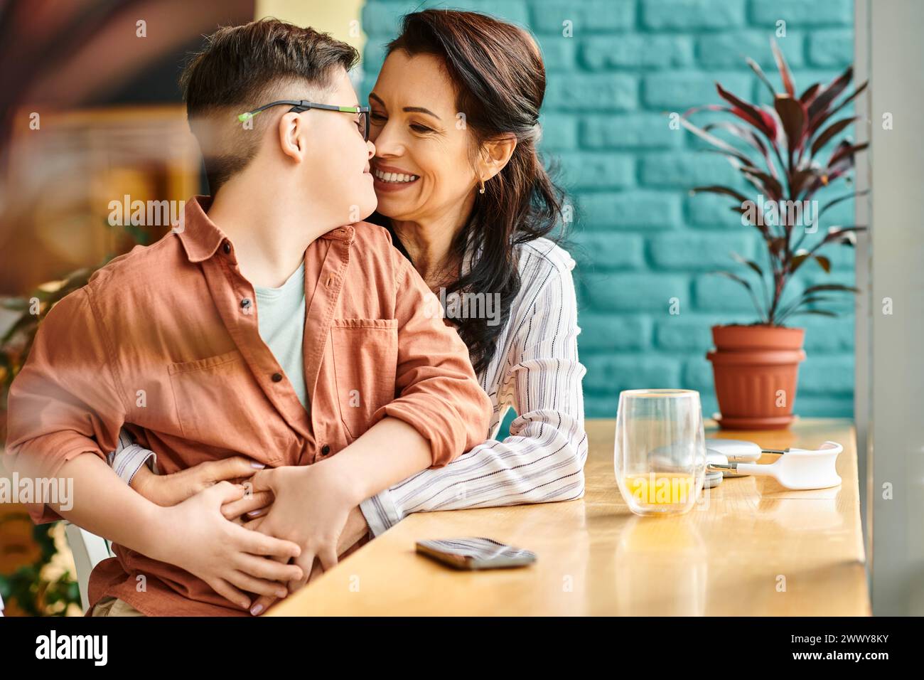 jolly mother spending quality time with her cheerful son with Down syndrome with smartphone ...
