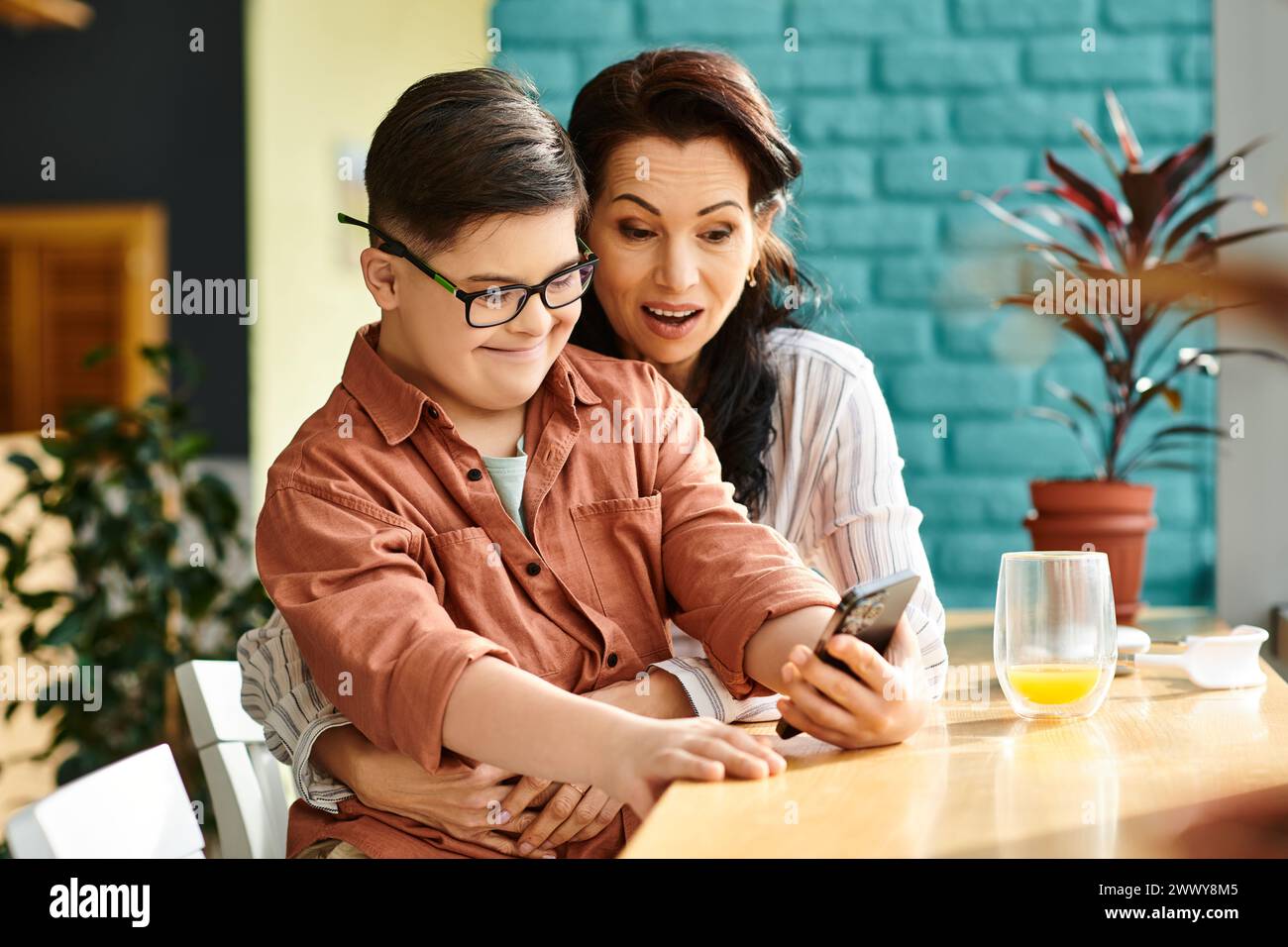 jolly mother spending quality time with her cheerful son with Down syndrome with smartphone ...
