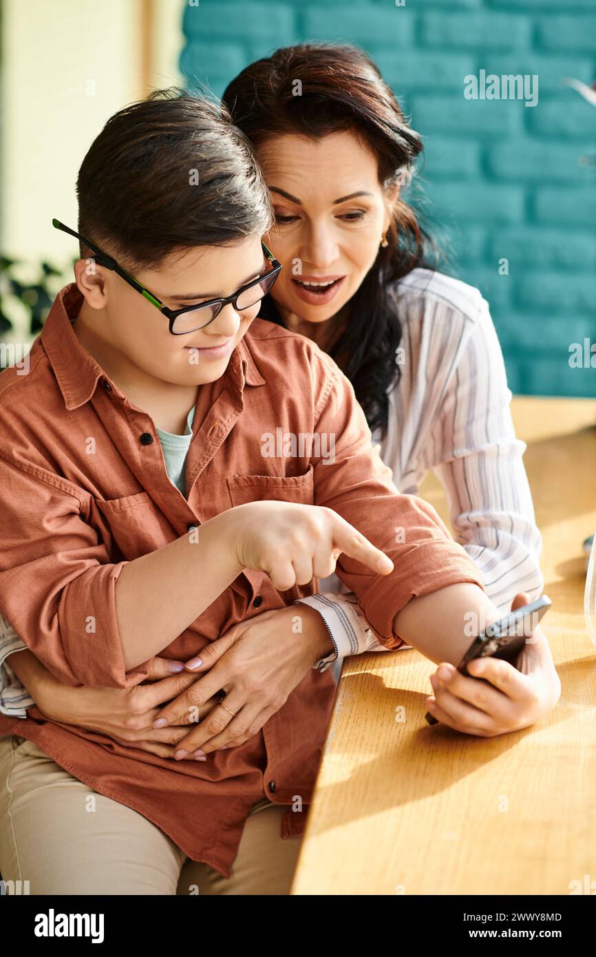 joyous inclusive boy with Down syndrome looking at phone next to his ...