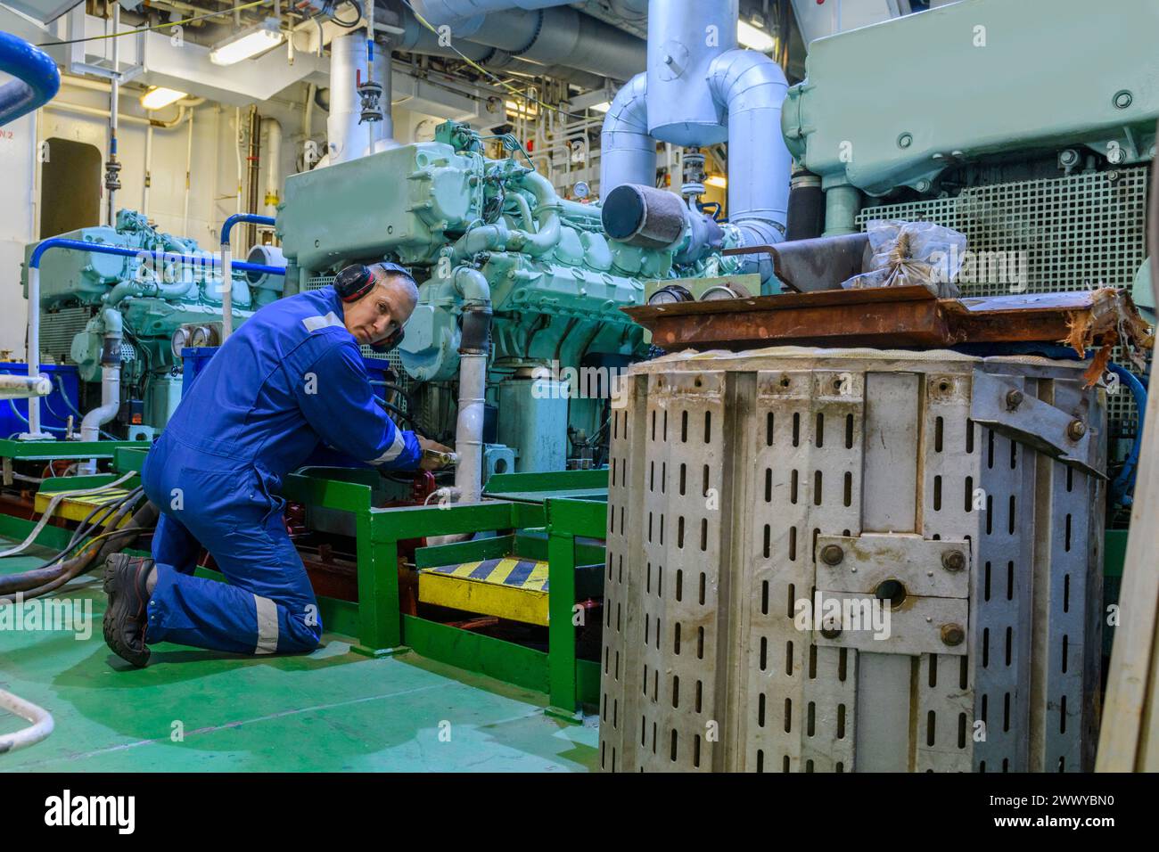 Marine Engineer in blue overall working in Engine room of ship. Work at ...