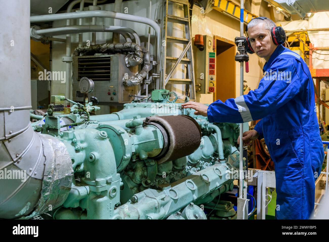 Marine Engineer in blue overall working in Engine room of ship. Work at ...