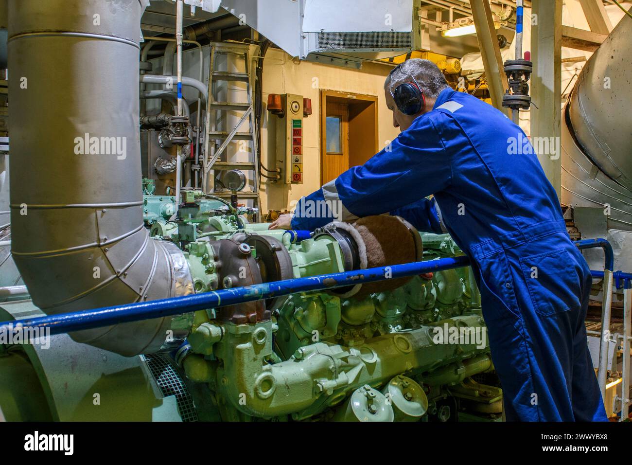 Marine Engineer in blue overall working in Engine room of ship. Work at ...