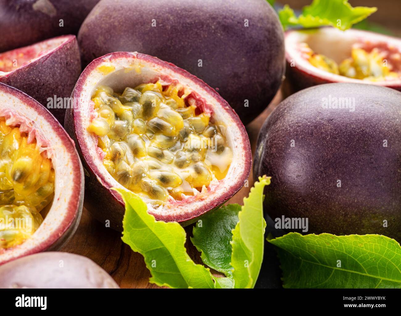 Ripe passion fruits with passion fruit seeds and passionfruit leaves on a gray stone table. Nice ...
