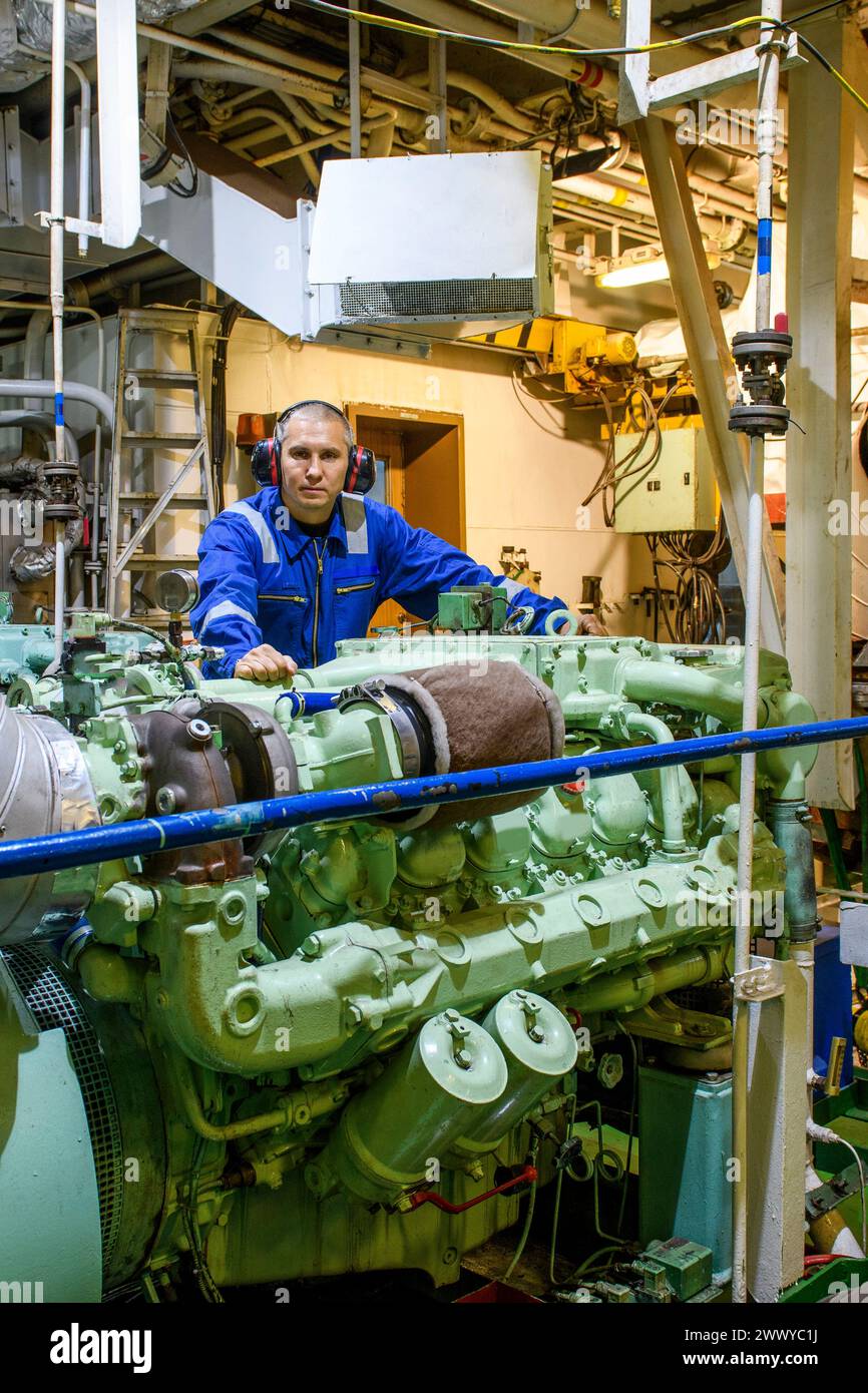 Marine Engineer in blue overall working in Engine room of ship. Work at ...