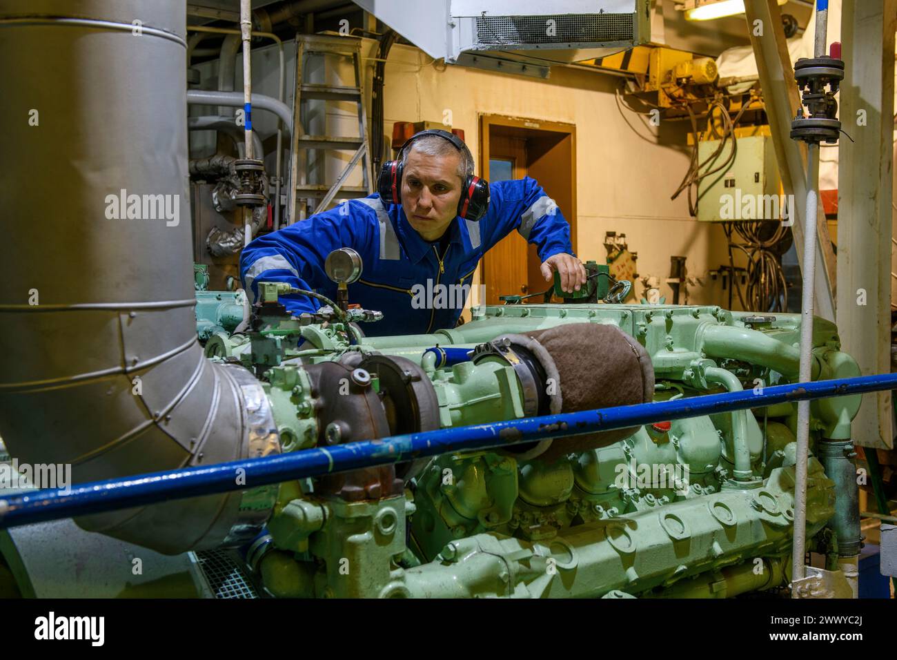 Marine Engineer in blue overall working in Engine room of ship. Work at ...