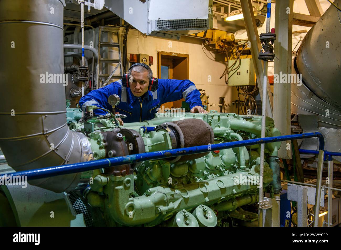 Marine Engineer in blue overall working in Engine room of ship. Work at ...