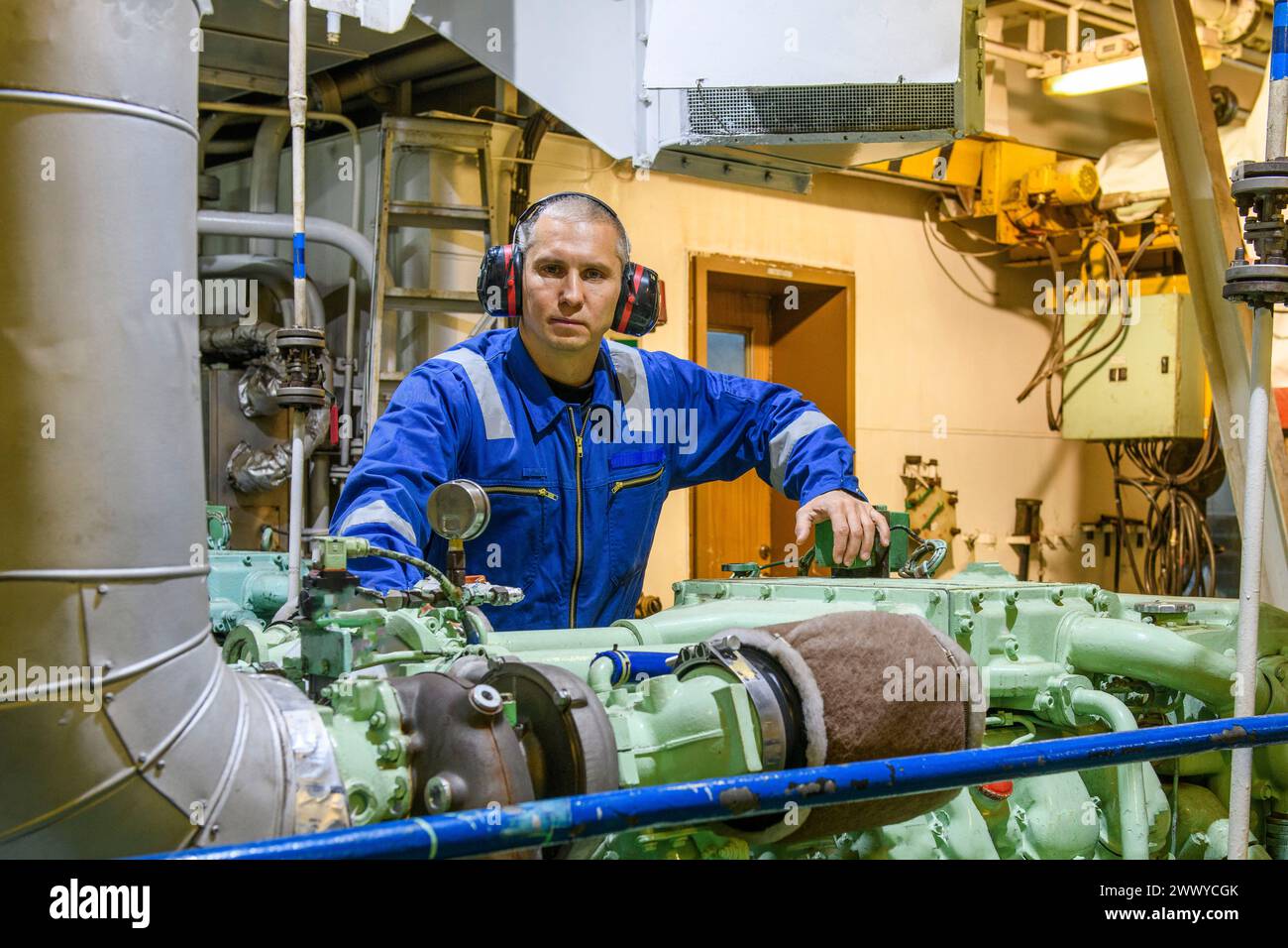 Marine Engineer in blue overall working in Engine room of ship. Work at ...