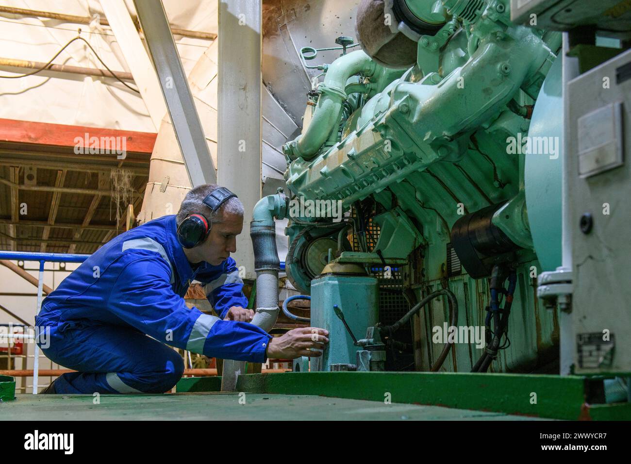 Marine Engineer in blue overall working in Engine room of ship. Work at ...