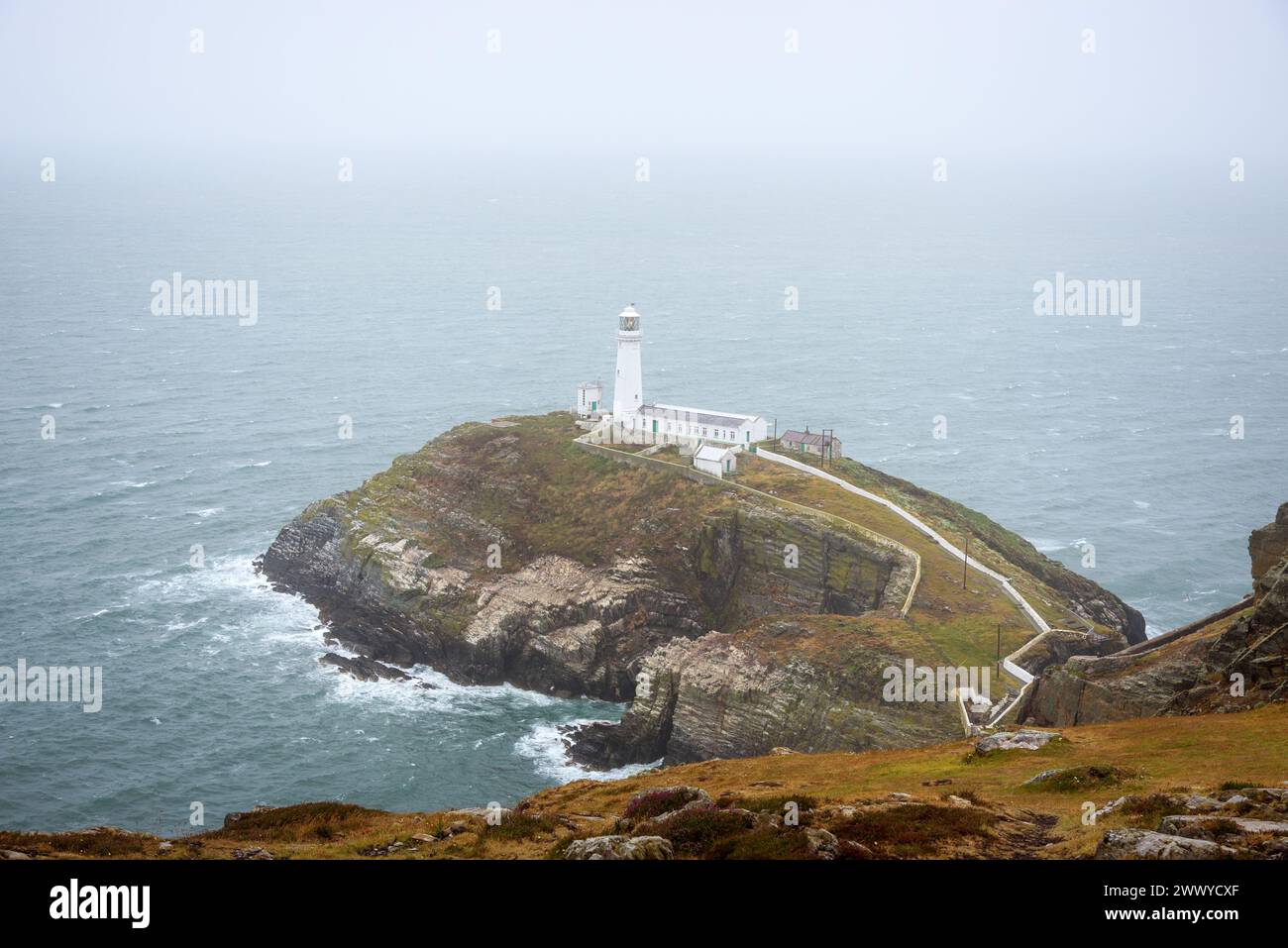 Historic lighthouse on the top of a small rocky islanfd off a rugged ...