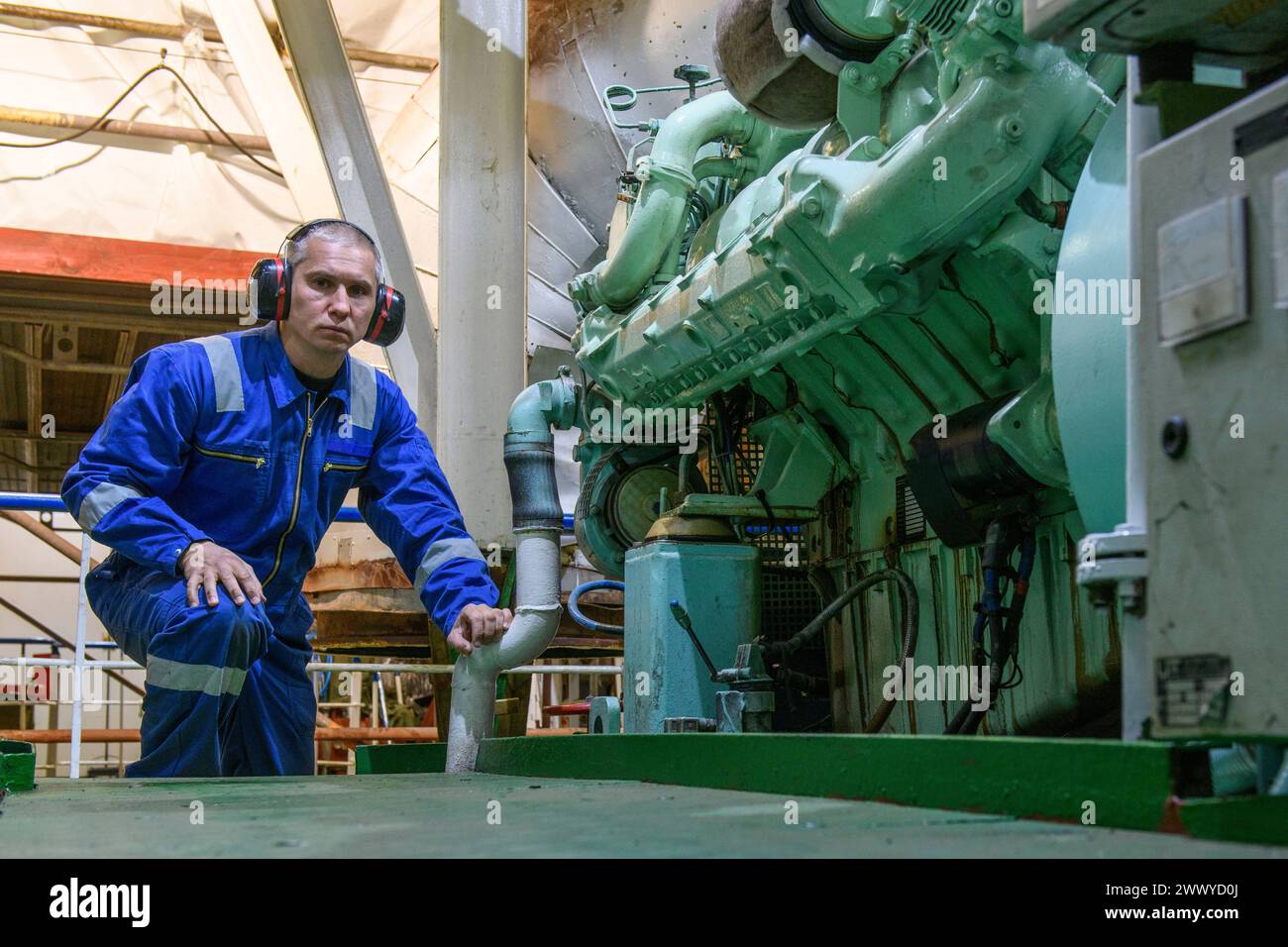 Marine Engineer in blue overall working in Engine room of ship. Work at ...