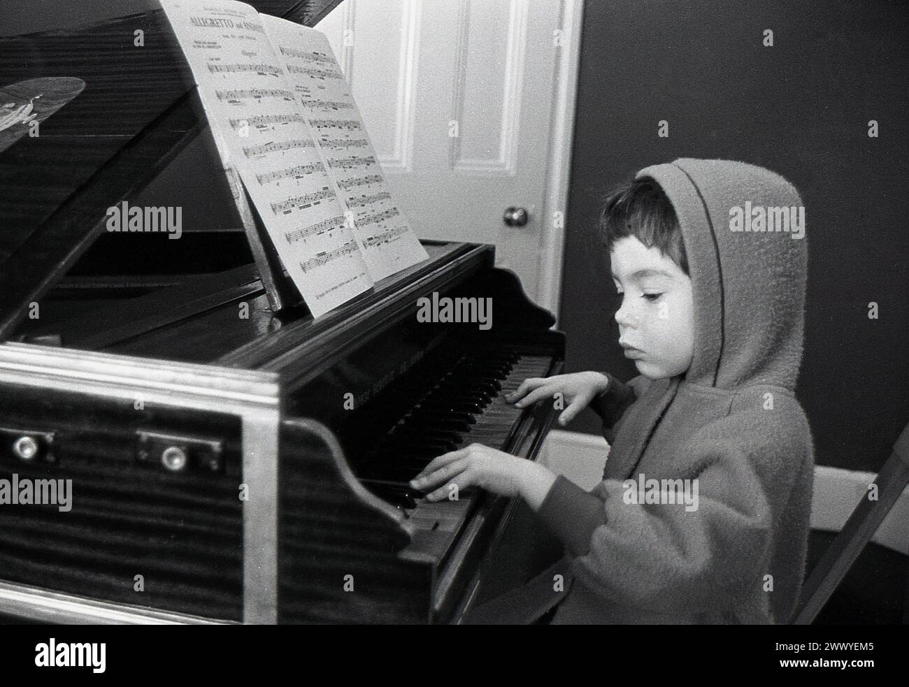 1970s, historical, a young boy in a hooded fleece top sitting playing a ...