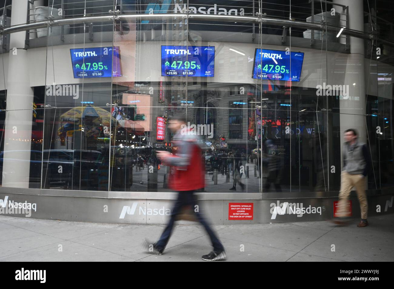 New York, USA. 26th Mar, 2024. Pedestrians walk past the Nasdaq ...