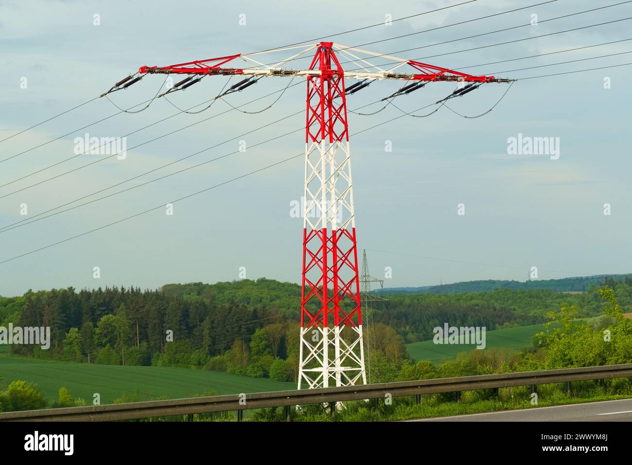 A red and white power pole stands on the side of a road, serving as ...