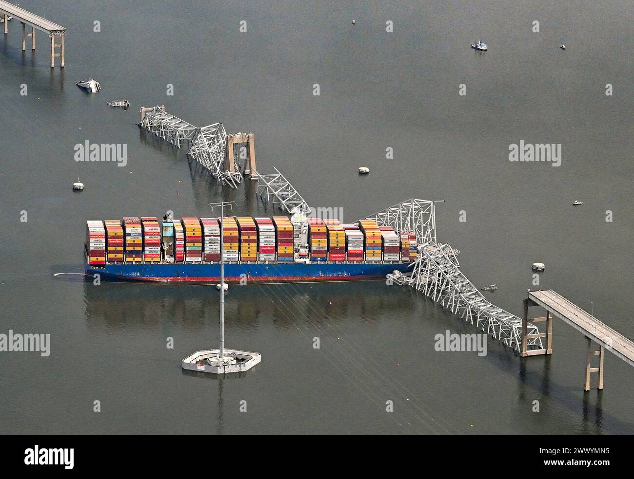 A damaged container ship rests next to a bridge pillar in the Patapsco ...
