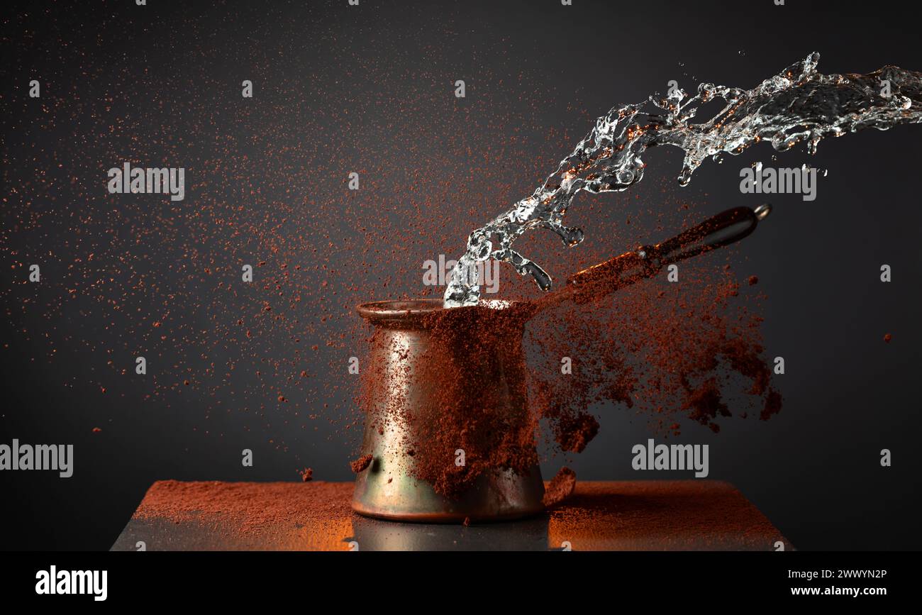 Black coffee making. Old copper cezve, water splashes, and grounded ...