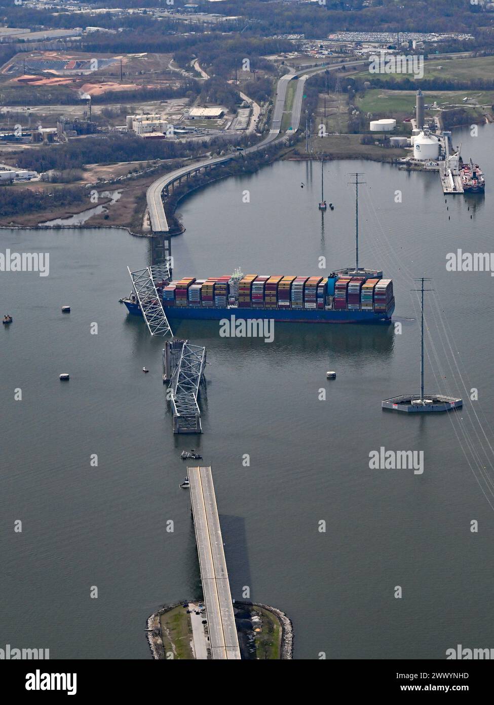 A damaged container ship rests next to a bridge pillar in the Patapsco ...