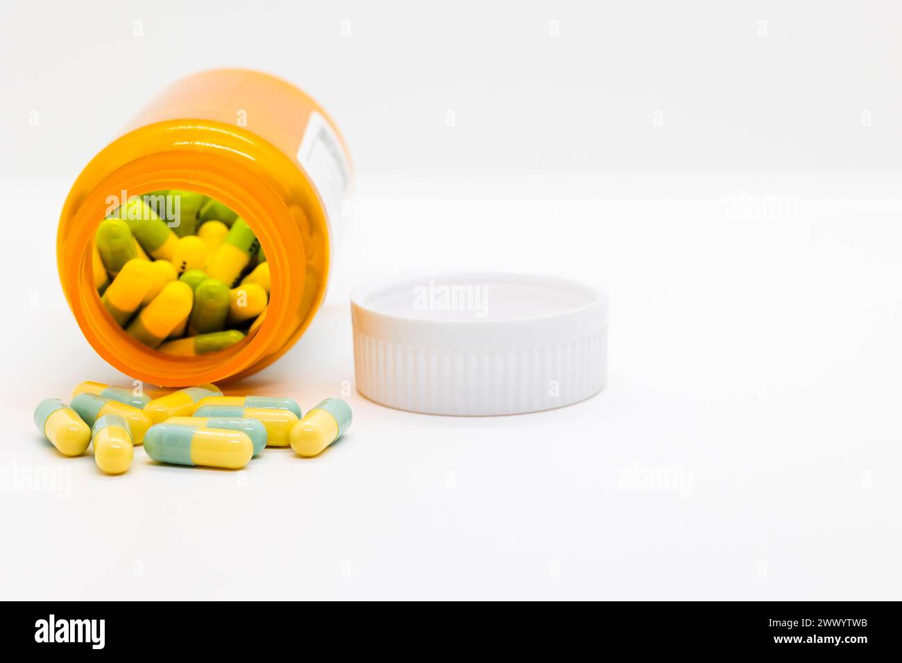 Generic green and yellow pills laying in front of a pill bottle with ...