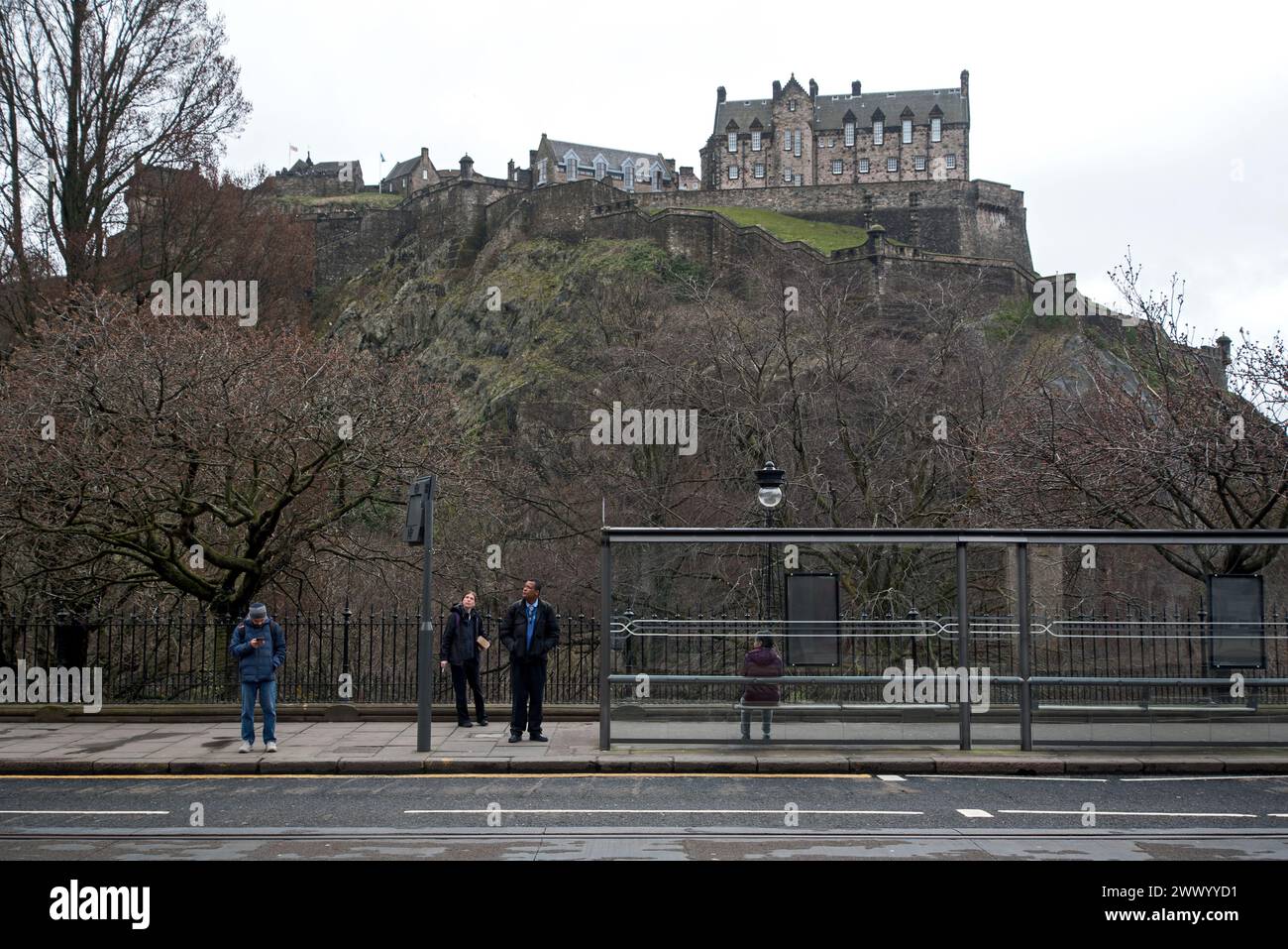 People waiting on an overcast day at a bus stop on Princes Street with ...