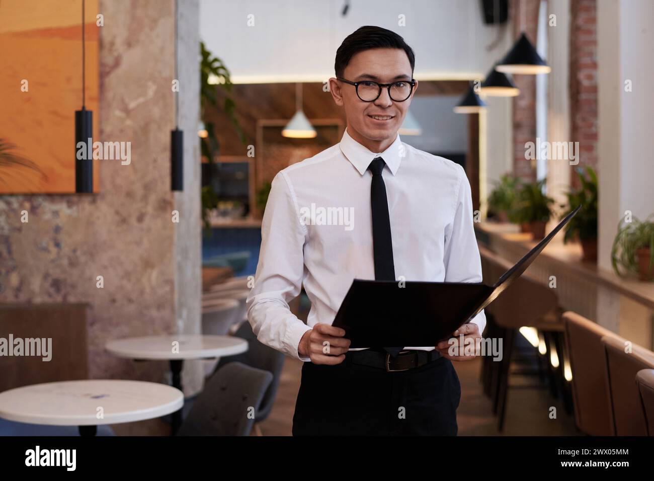 Medium portrait of young Asian restaurant manager wearing eyeglasses ...