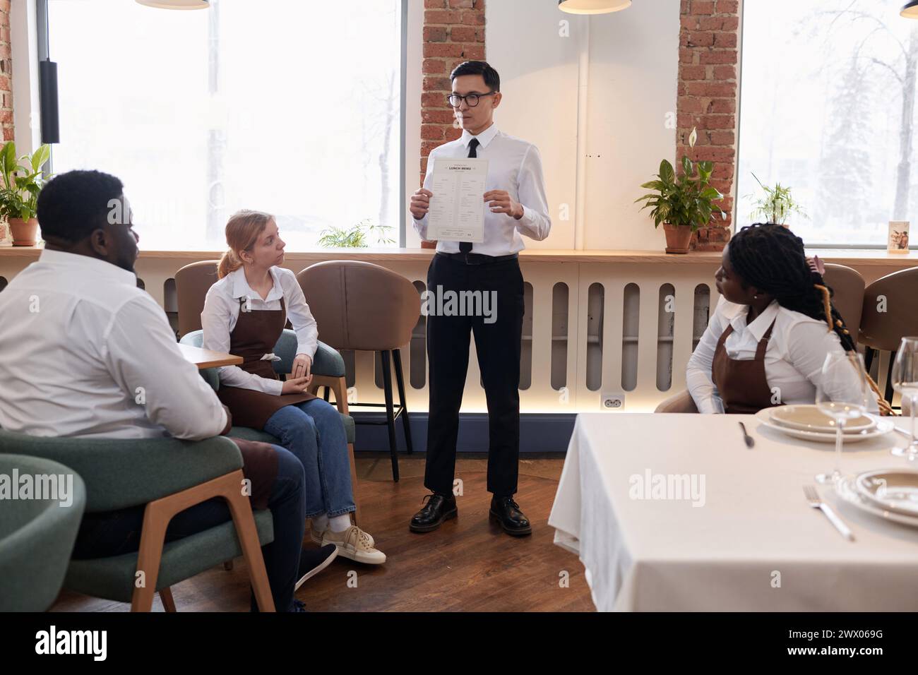 Young Asian manager working in modern restaurant showing new menu to ...