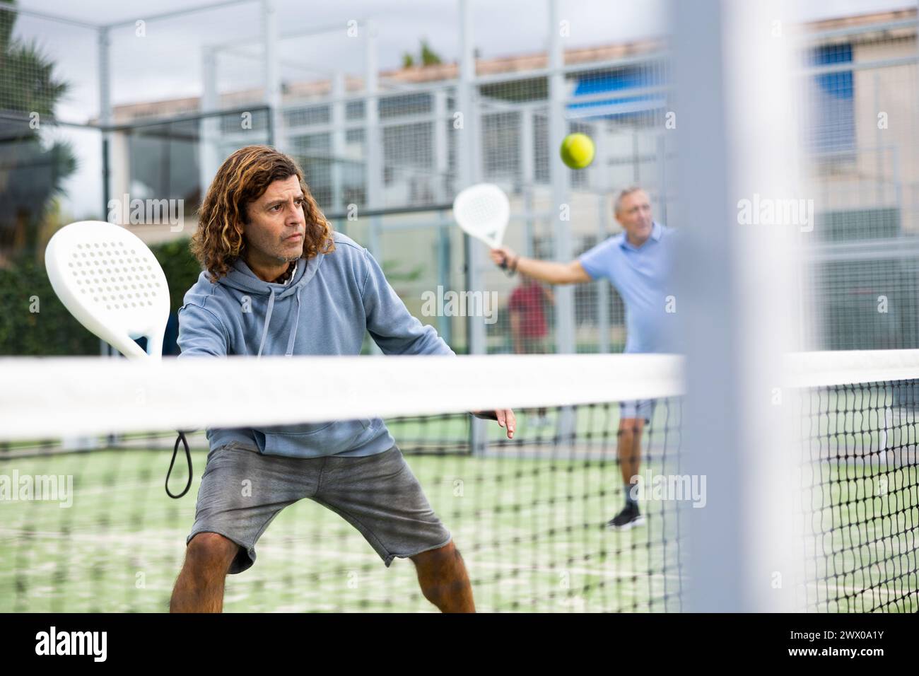 Male players playing padel in a padel court outdoor behind net Stock ...