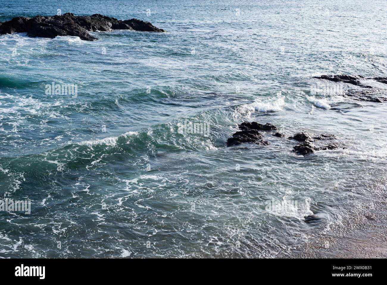 Seaside of a beach with small foaming waves. Sunny day, calm sea water ...