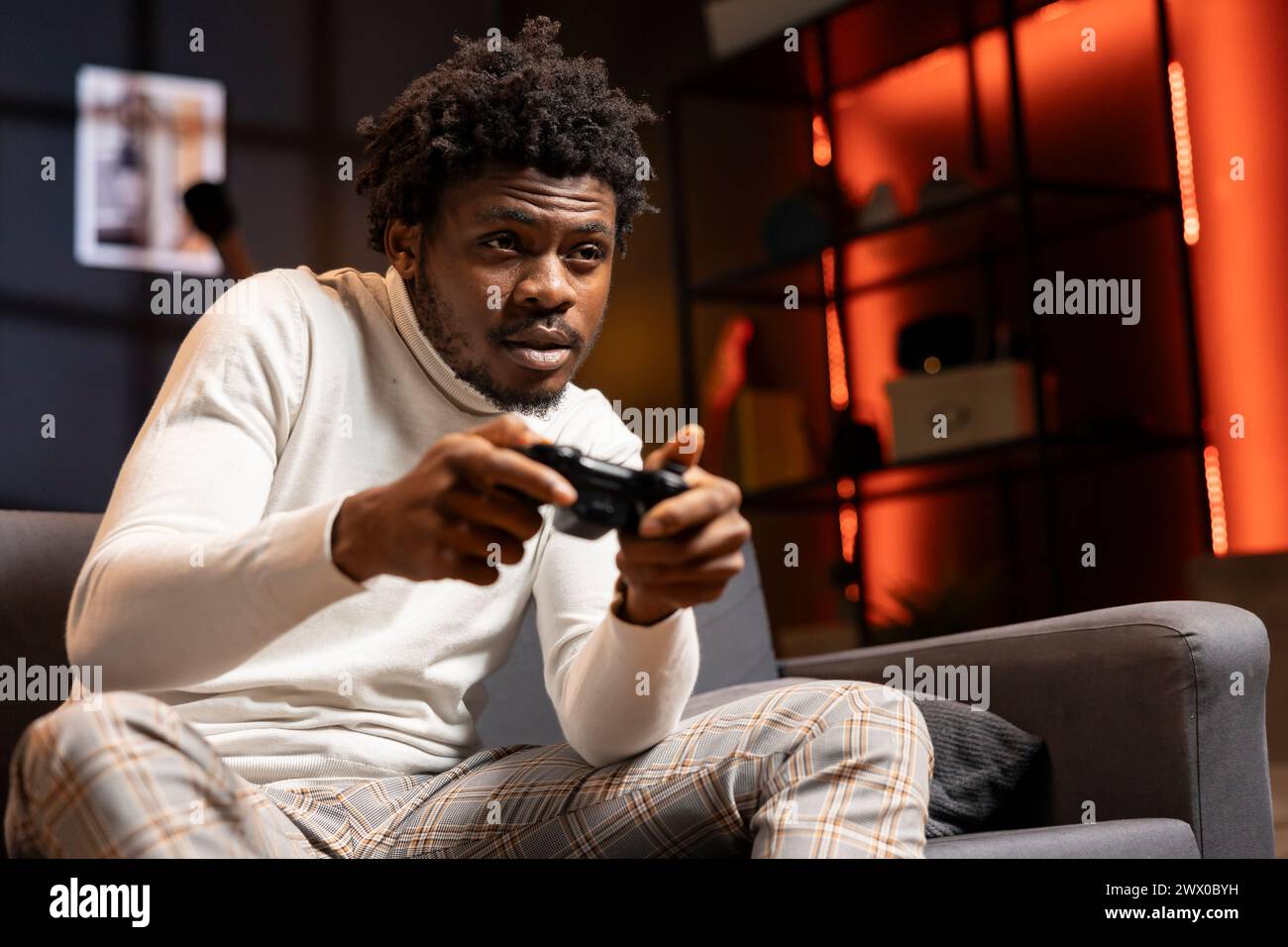 Gamer playing videogames on console late at night in orange neon ...