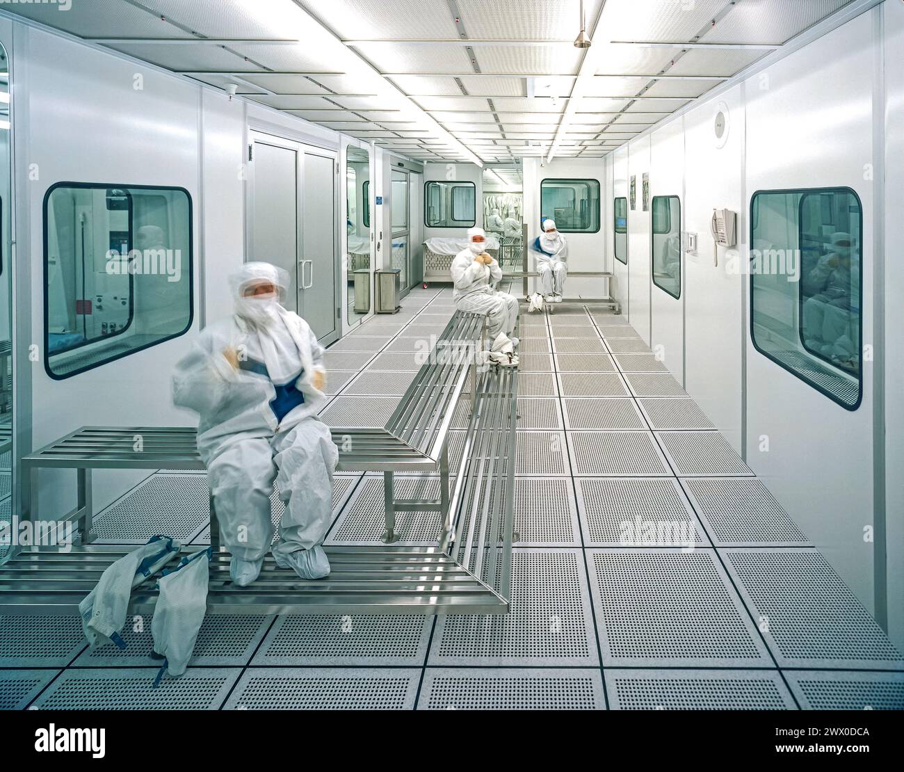 Seated workers get gowned up to work in clean rooms. There is a ...