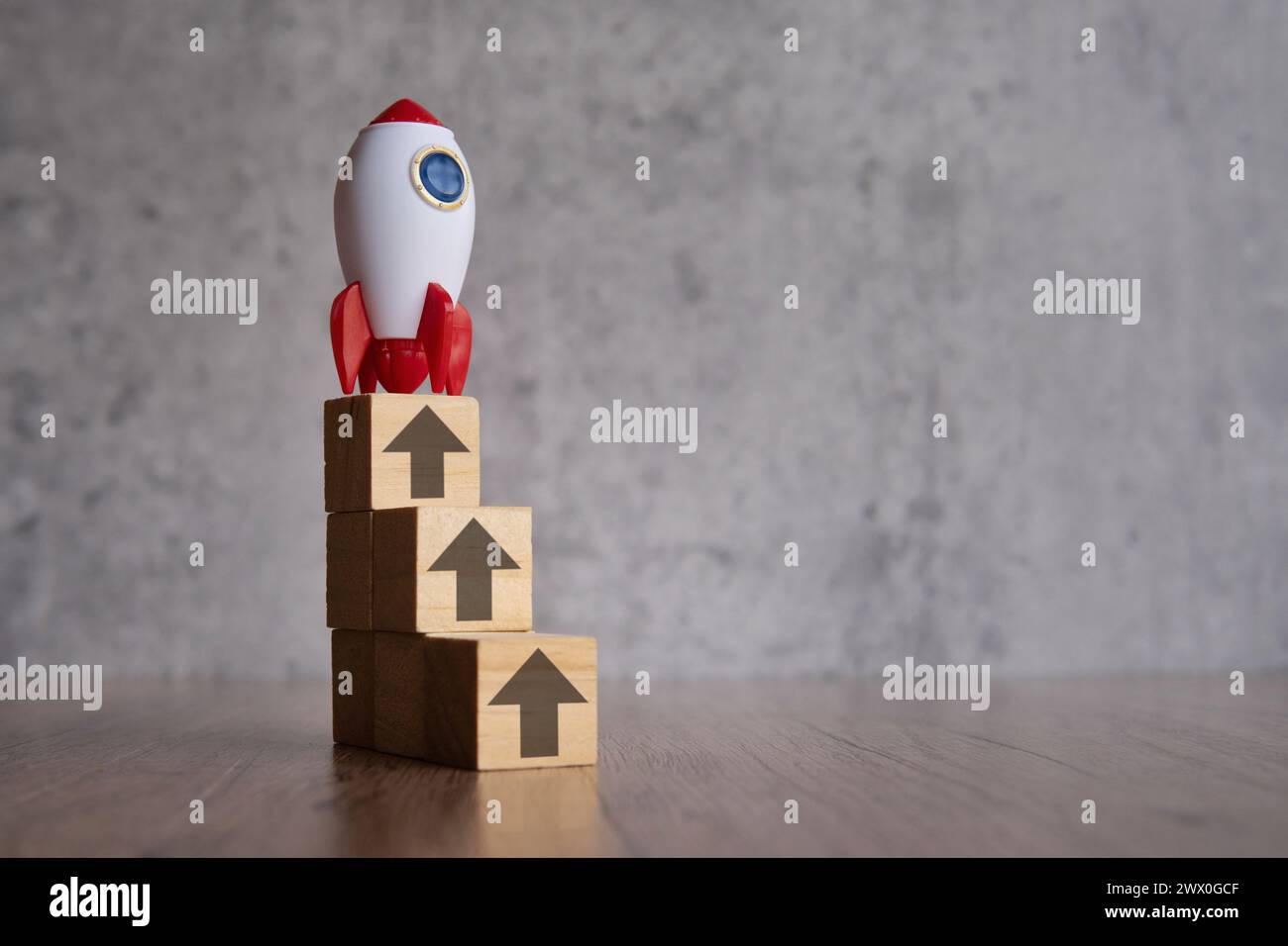 A stack of wooden blocks with arrows pointing upwards and rocket. Copy ...