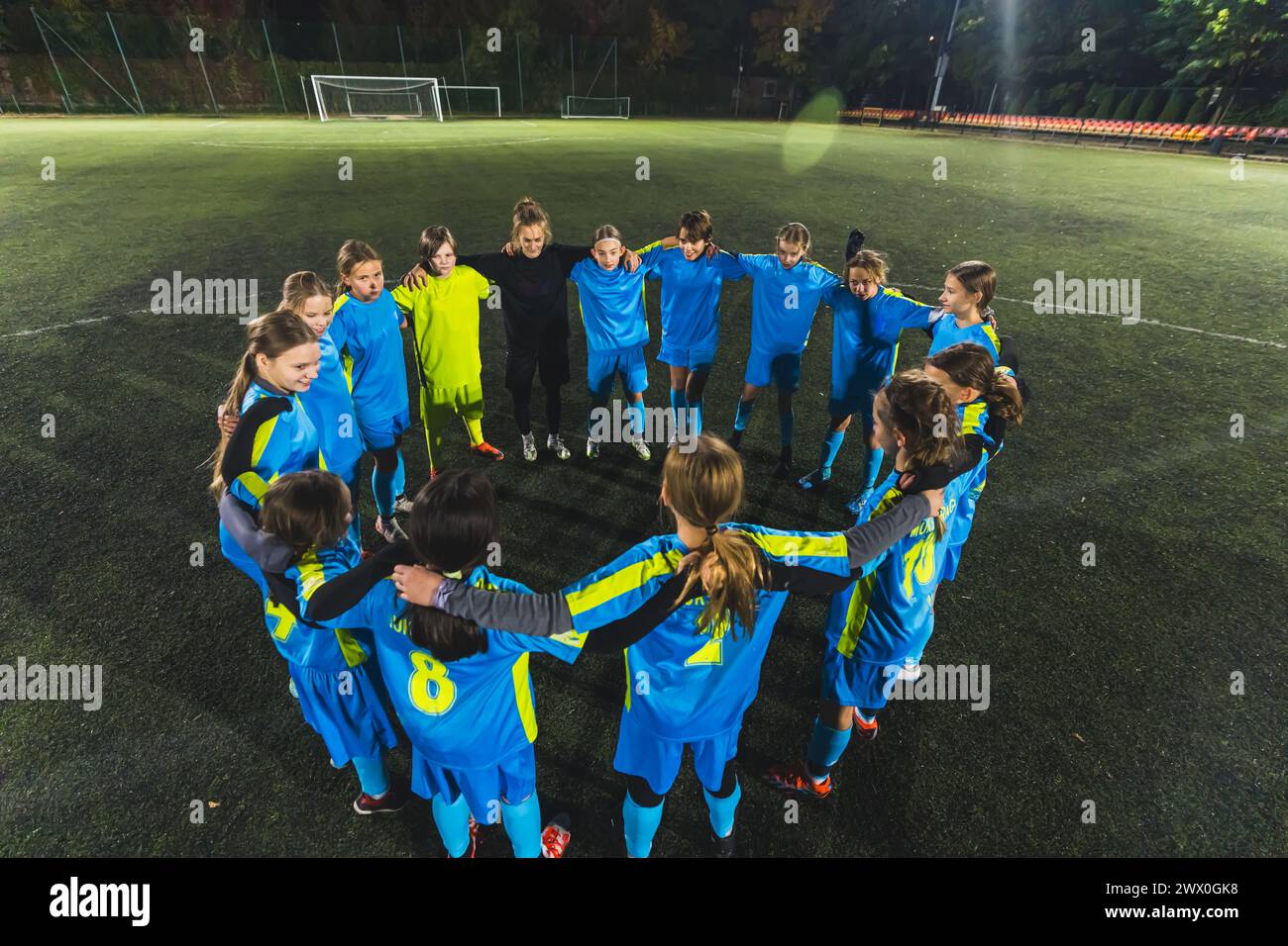 young school girls and their female coach standing in a circle and ...