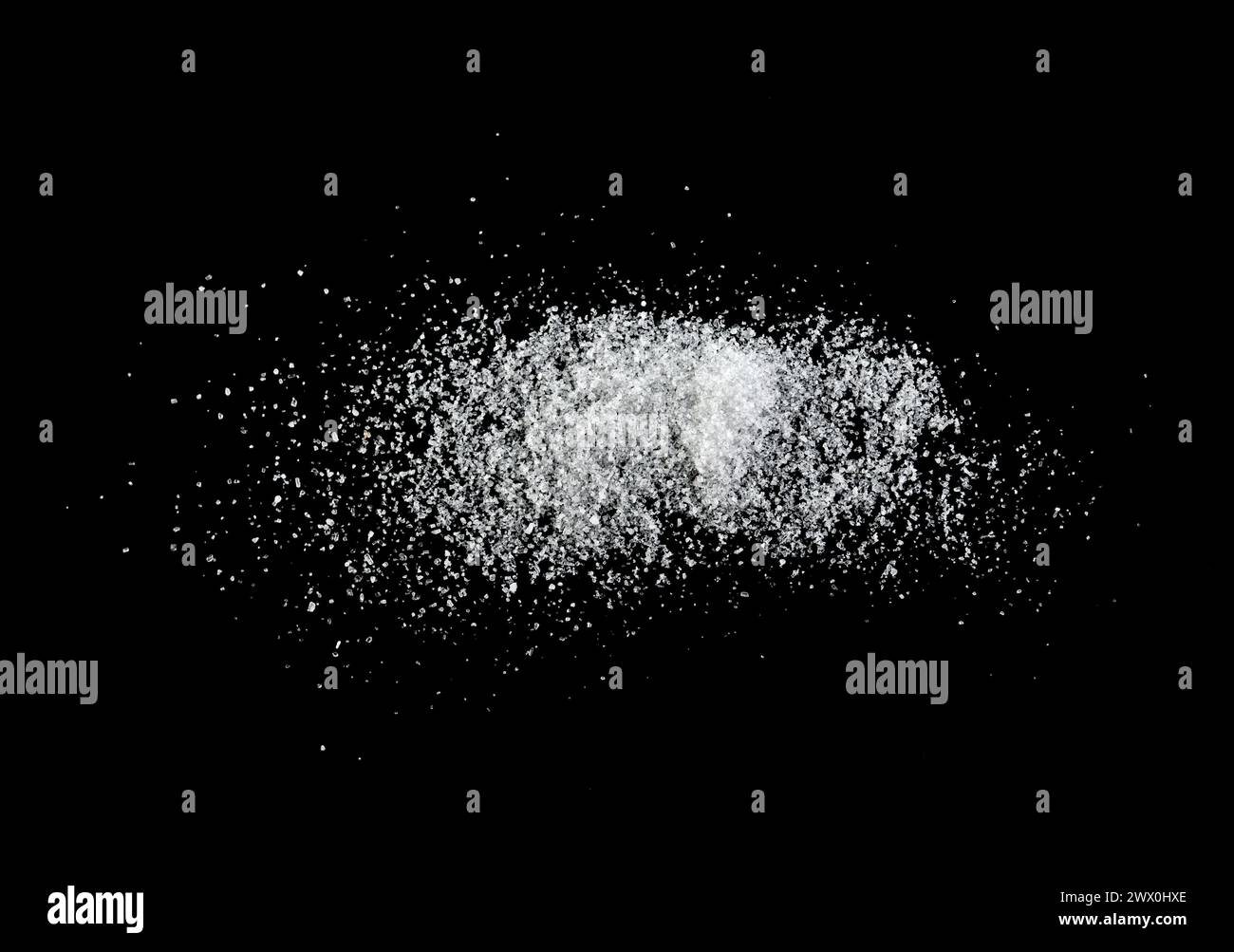 Spilled white sea salt on a black background. clear crystalline pebbles ...