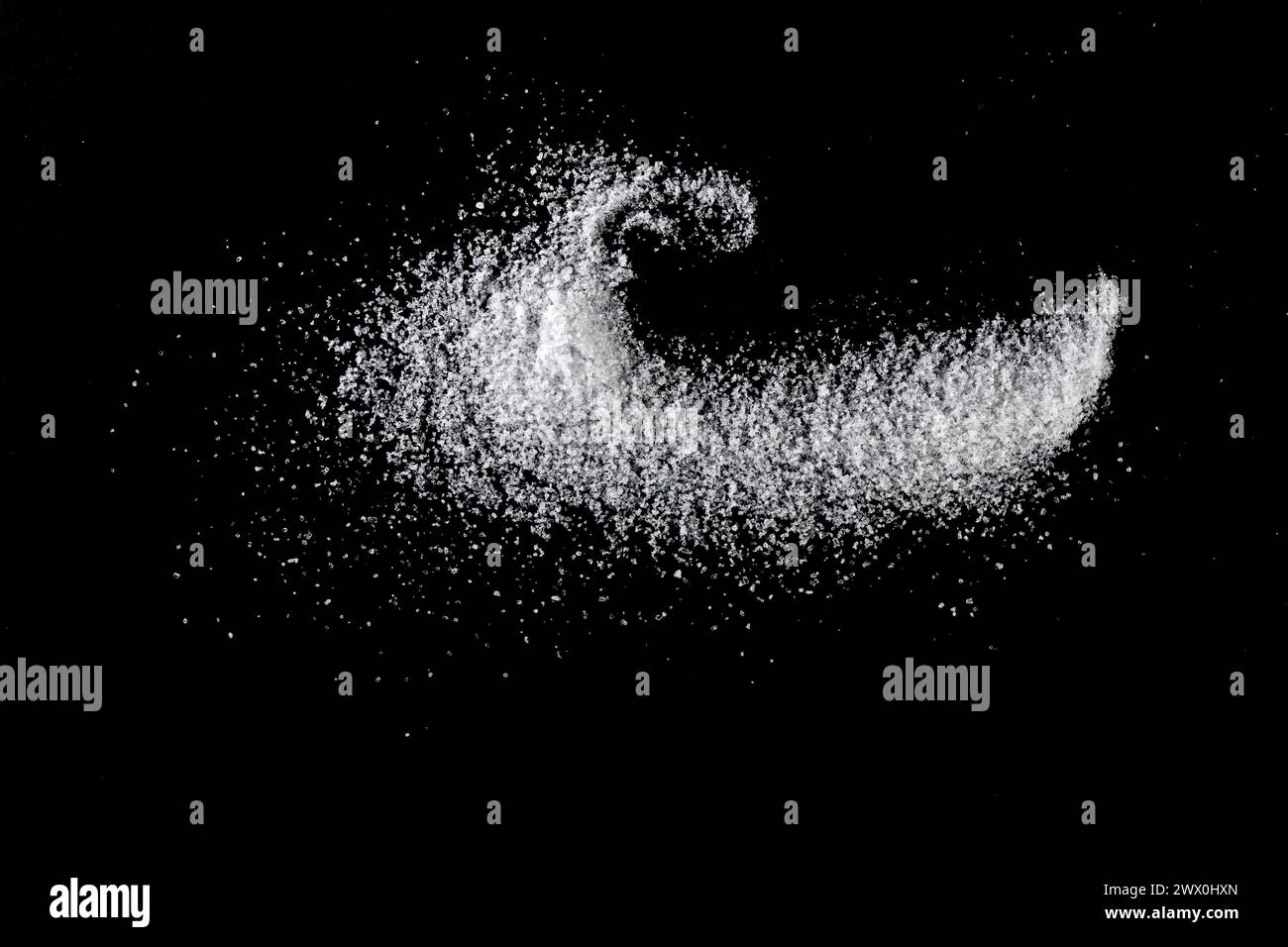 Spilled white sea salt on a black background. clear crystalline pebbles ...