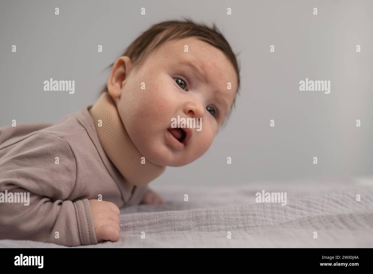 Portrait of a newborn baby lying on his stomach in an orthopedic collar ...