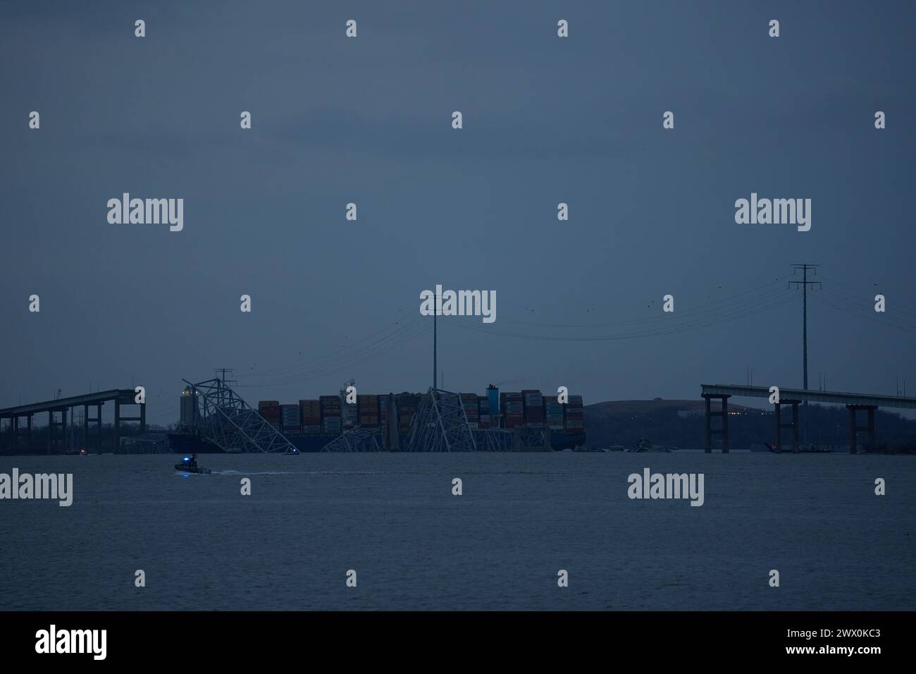A container ship rests against wreckage of the Francis Scott Key Bridge ...
