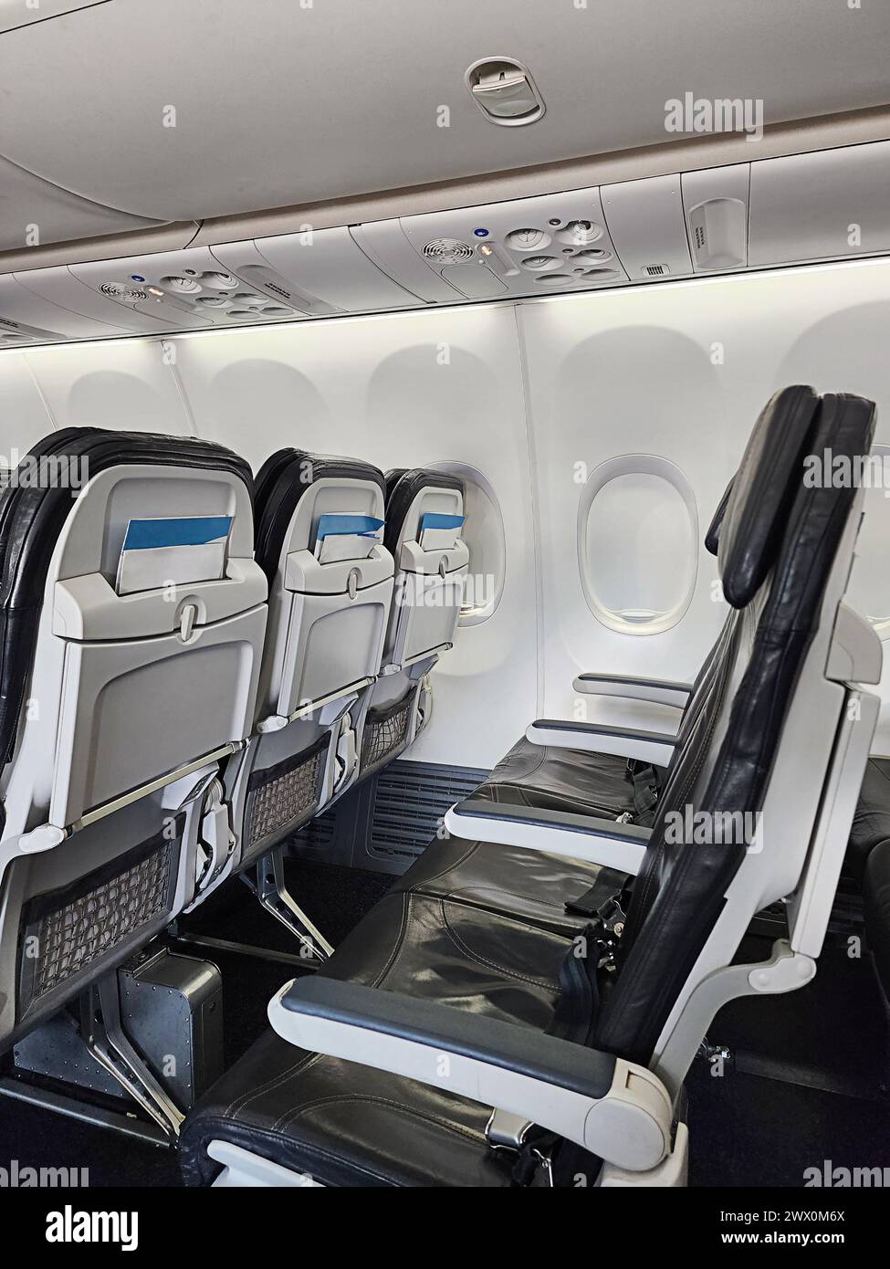 An empty airplane seat row viewed from across the aisle Stock Photo - Alamy